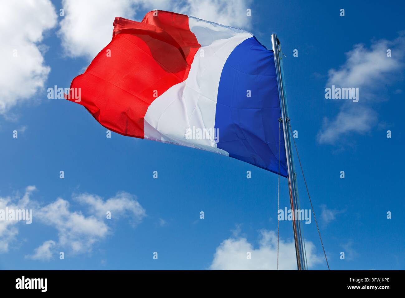 French national flag waving on a flagpole against a bright blue sky ...