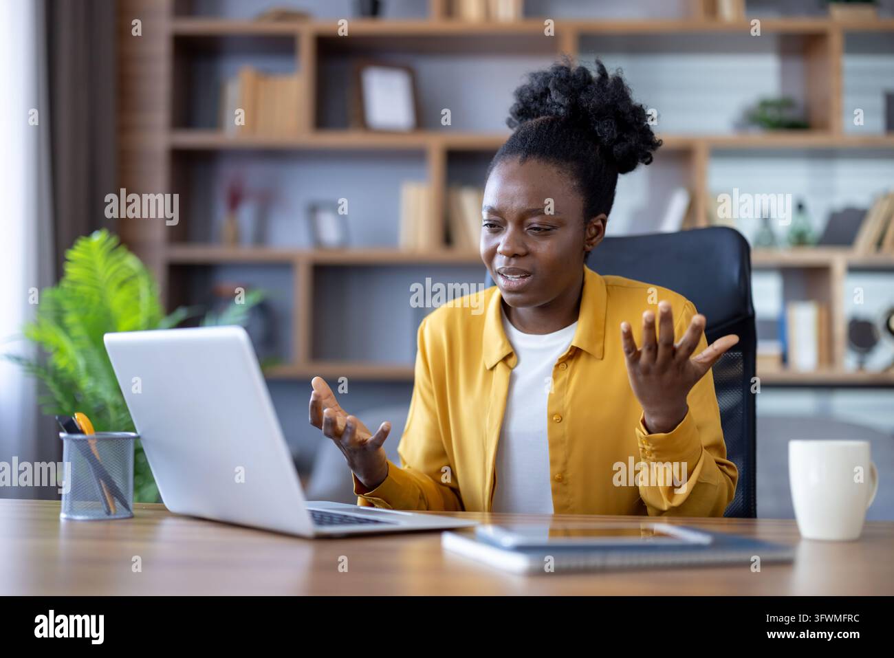 Woman sits at desk with laptop in modern home office, explaining ideas ...