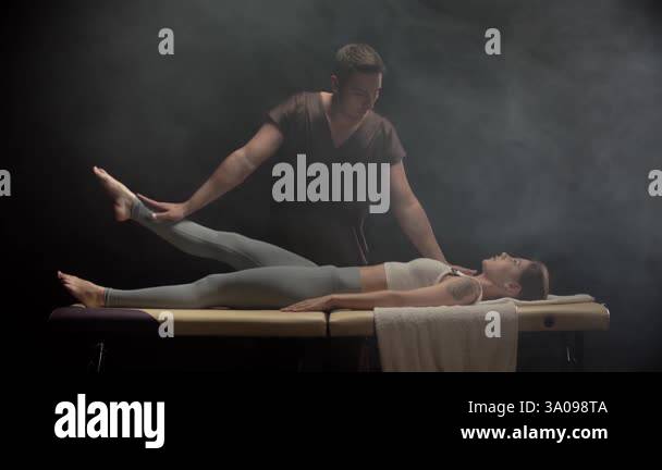 Young woman receiving leg stretches from a physiotherapist on a massage ...
