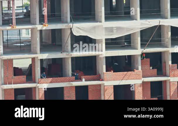 Construction workers building exterior brick walls on a new residential ...