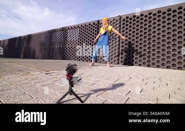 Energetic blonde dancer recording urban dance choreography outdoors ...