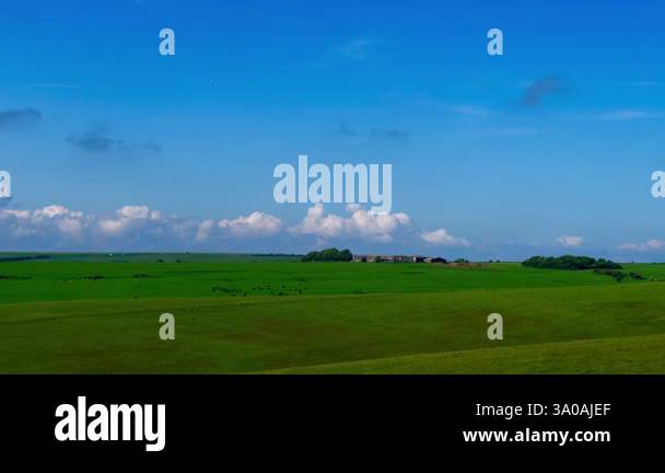 Green field stretching into the distance, framed by a bright blue sky ...