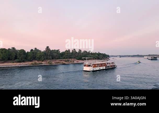 Evening scene on the Nile, featuring a cruise boat navigating the river ...