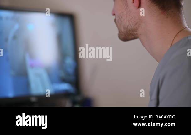A man is intently focused on watching a large screen, showcasing the ...