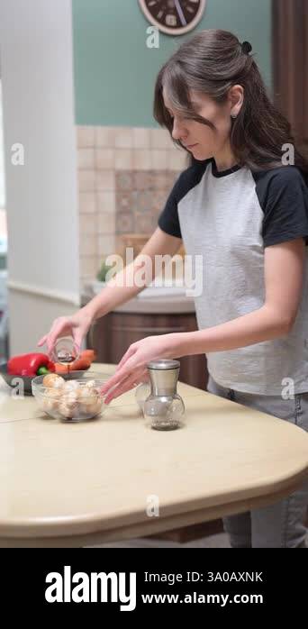 Woman grinding salt with manual mill over fresh mushrooms, preparing ...
