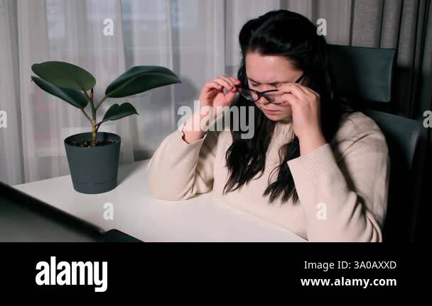 Tired woman working at home with laptop holding eyeglasses rubbing eyes ...