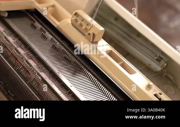 Close-up of artisan hand moving carriage on a vintage manual knitting ...