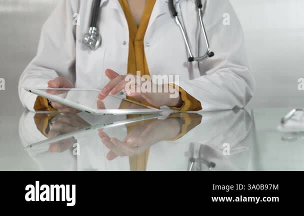 Female doctor, wearing yellow blouse under a medical coat, is using ...