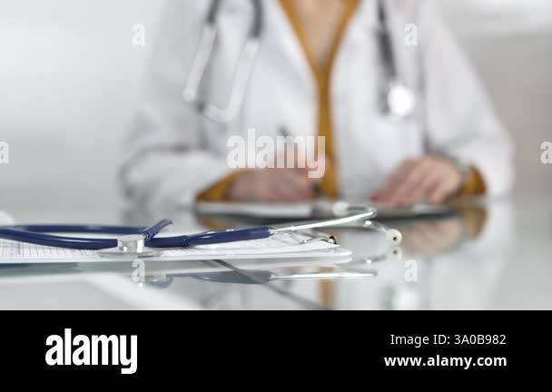 Stethoscope and medication history records form are on a glass table ...