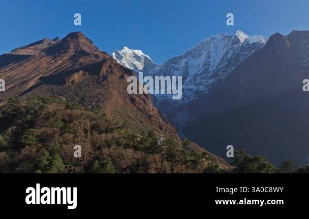 Sunlight glinting off snow covered Mount Everest peak, casting dramatic ...