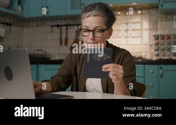 A mature woman completes an online form while holding a US passport at ...