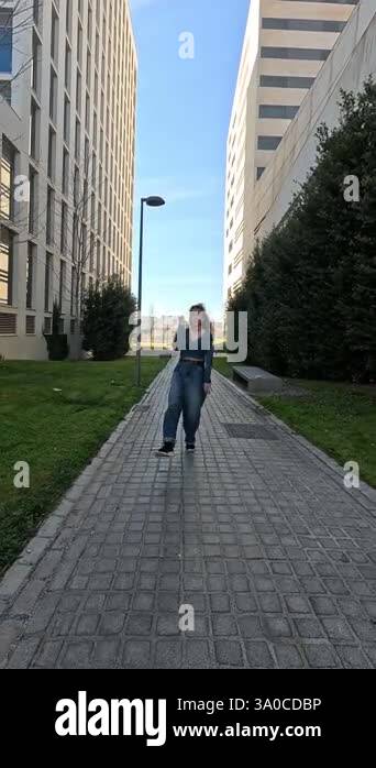 Young woman running dynamically between sleek modern buildings ...