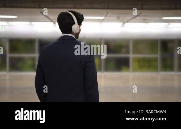 Business man turn around and listening music from headphone while ...