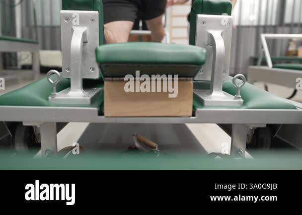 Man practicing kneeling stretch on pilates reformer with assistance to ...