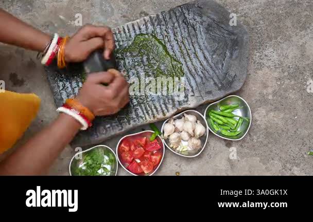 Grinding coriander chutney on stone grinder.Indian Woman hands grinding ...