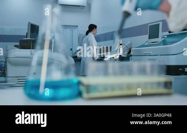 Close-up of test tubes with liquid and pipette pouring substance in ...