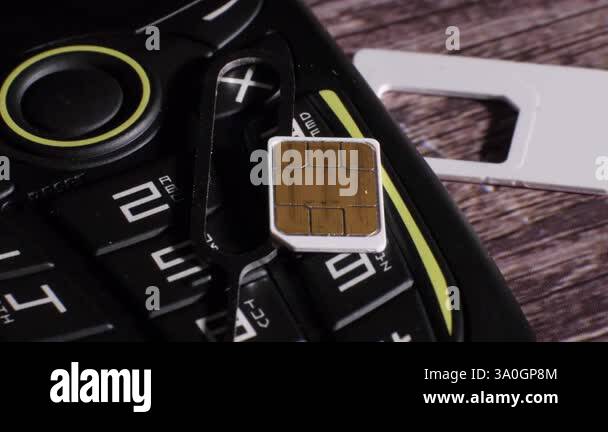 Closeup shot of a black and yellow cellphone and the parts of the sim ...
