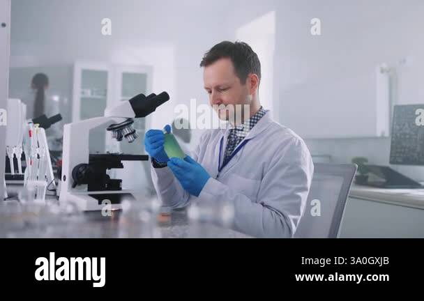 Shot of serious focused young Caucasian man wearing white lab coat ...