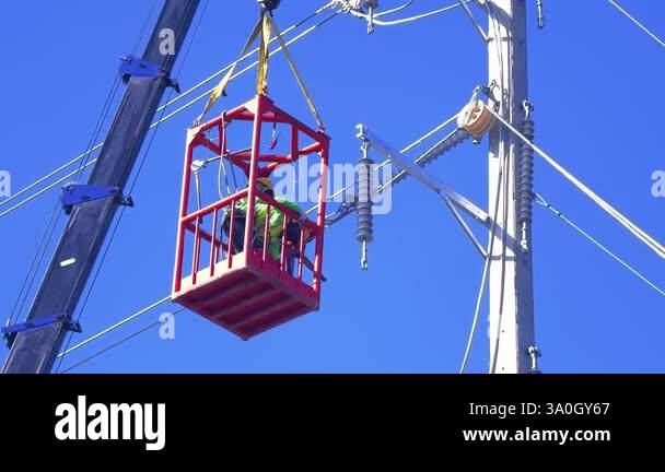 Two skilled workers on a lift are ensuring safety during electrical ...