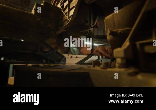 Low angle shot of worker controlling with saw machine and cutting wood ...