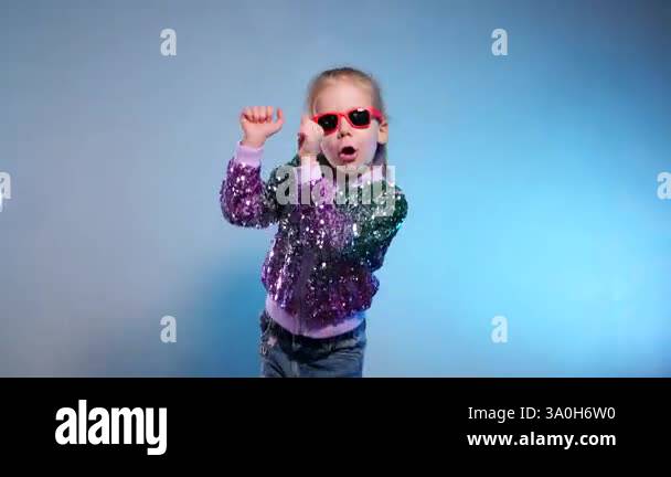 Smiling girl dancing funny in studio on colored background. Little ...
