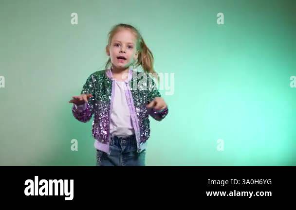 Smiling girl dancing funny in studio on colored background. Little ...