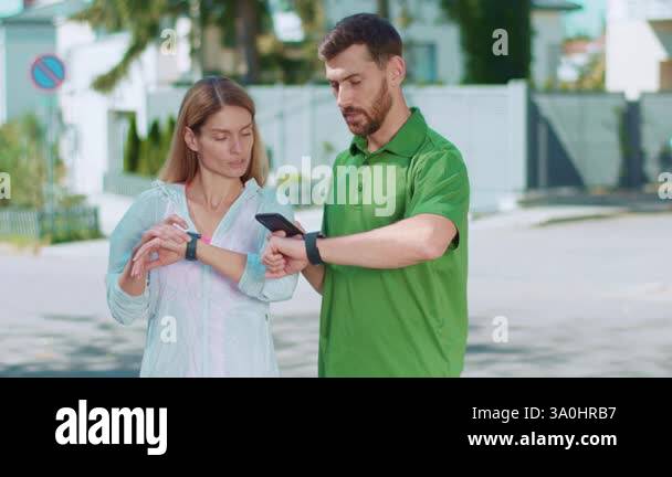 A couple examines their smartwatches outdoors, highlighting the blend ...