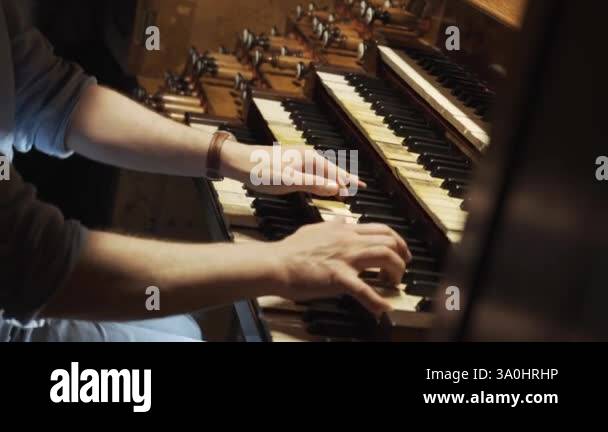 Expert organist plays a large church organ keyboard. Hands move quickly ...