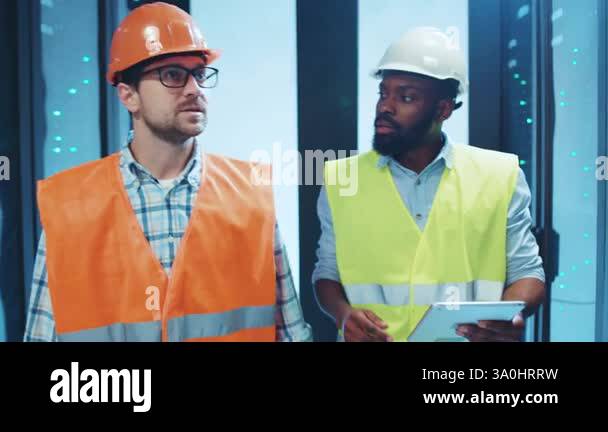 Two engineers dressed in appropriate safety gear are actively ...