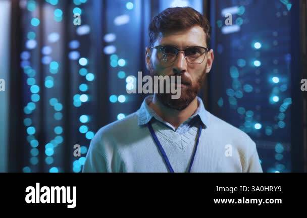 In a server room, a knowledgeable man with a beard and glasses studies ...