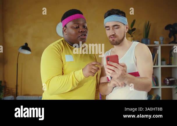 Two friends sit in a cozy living room, sharing a light moment as they ...