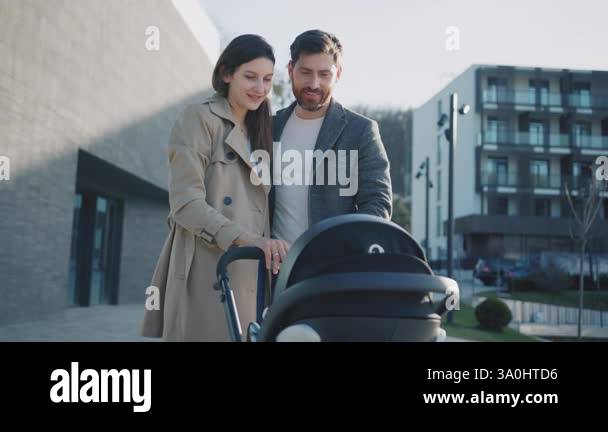 Young family stand with a pram near the lake. Husband and wife with ...
