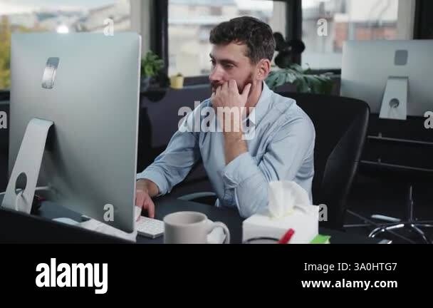 A focused man is seated at his desk, fully concentrating on his ...