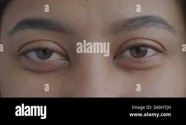 Close-up slow motion portrait of biracial womans eyes looking at camera ...