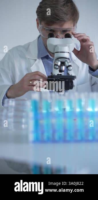 Male scientist researcher wearing lab coat and protective glasses, is ...