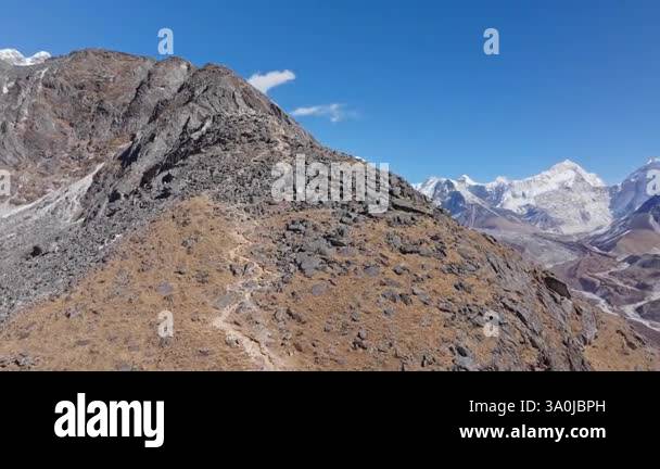 Towering Mount Everest rising above rugged terrain, exposing snow ...