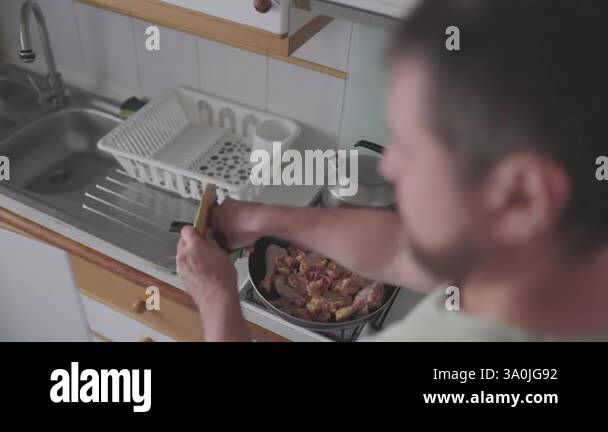 Man seasoning chicken meat with salt in a pan on a gas stove Stock ...