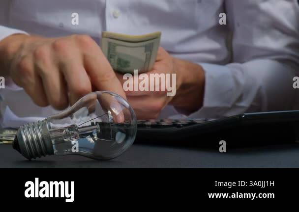 Electric light bulb. Man hands counting expenses on electricity ...