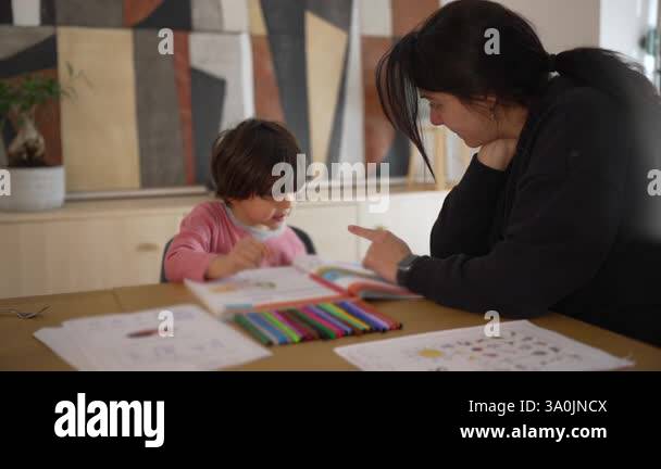 Child and parent studying together at a table, focused on a colorful ...