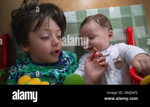 Young boy and baby lying on the floor, gazing at each other, baby ...