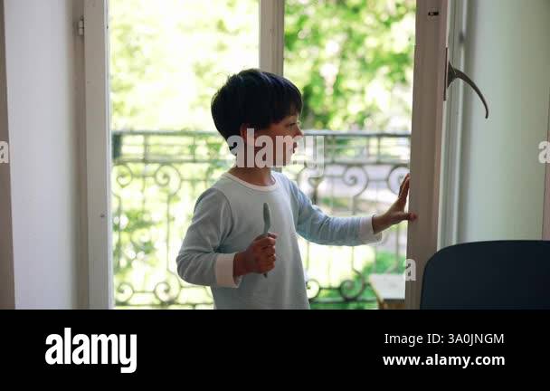 boy closing the window door after stepping out onto the balcony. his ...