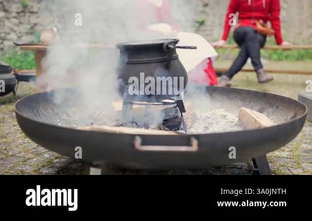 Boiling cauldron over an open fire at a medieval festival, with a ...