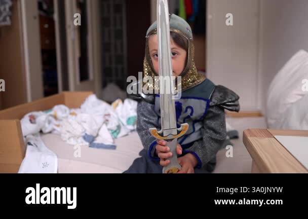 Young boy dressed as knight holding toy sword close to camera, showing ...