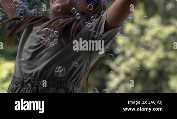 Girl with hair flowing, arms raised, and bubbles floating around her in ...