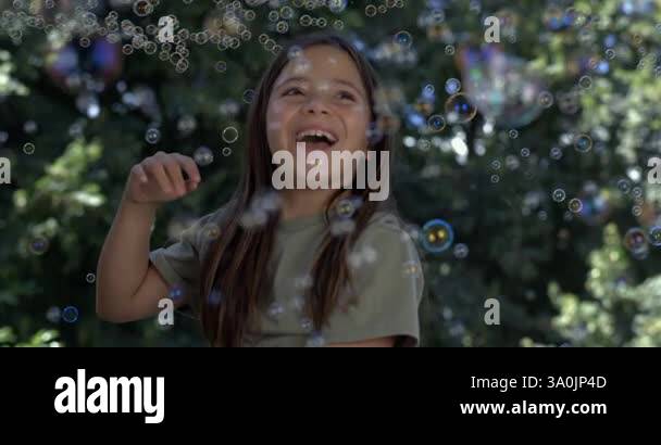 Young girl laughing while playing with bubbles in slow motion at 800 ...