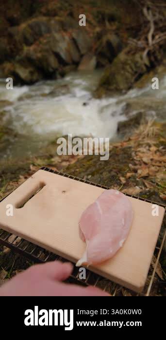 Vertical footage of male hands puts chicken fillet on wooden board near ...