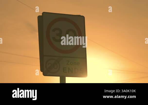 Speed restriction sign against golden sky. Street sign shadow in rising ...