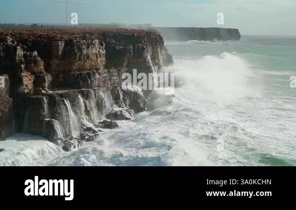 Massive ocean waves crash against towering coastal cliffs, sending ...
