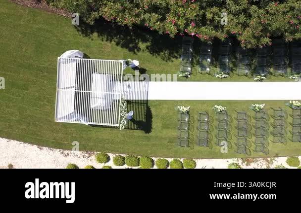 Aerial view of a luxurious outdoor wedding setup with a white aisle ...
