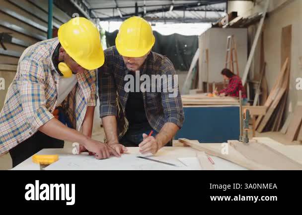 Two construction workers reviewing blueprints, wearing helmets, and ...
